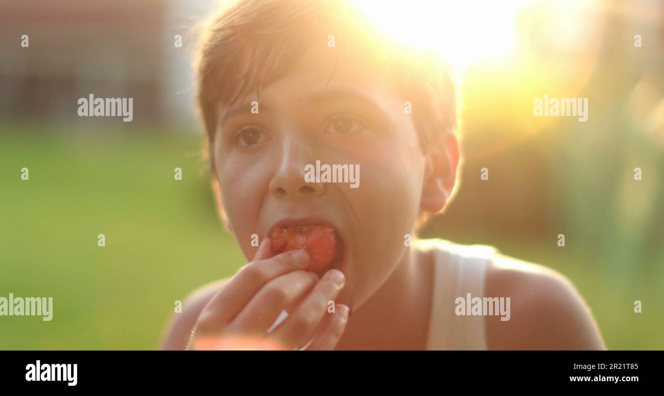 Child boy snacking fruit outdoors during sunset golden hour time Stock ...