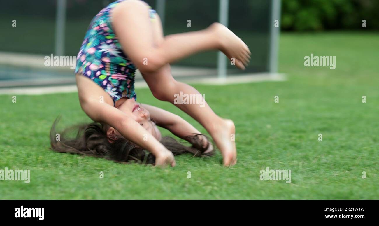 Child girl doing somersault outdoors. Little kid tumbling outside in ...