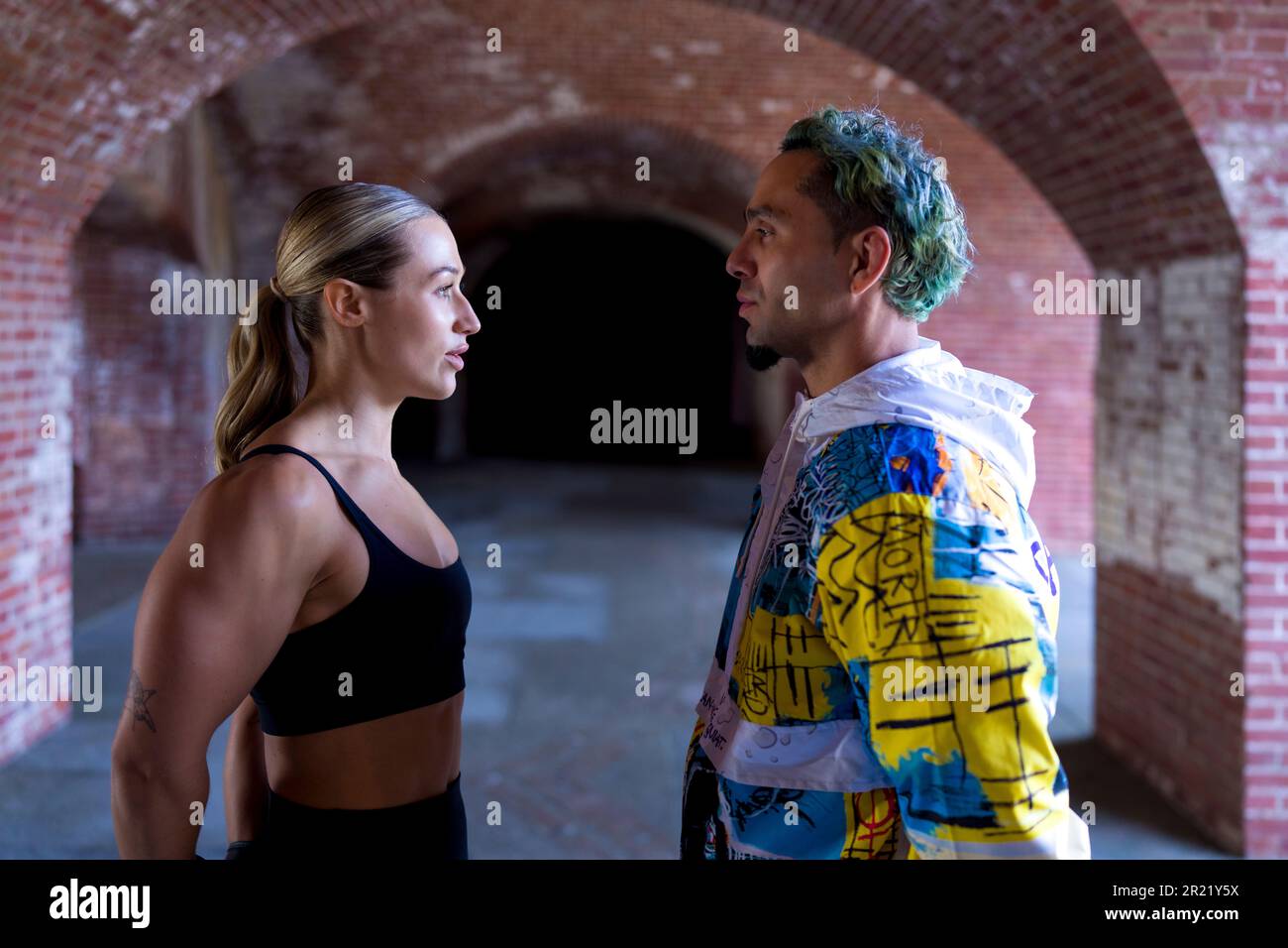 Male and Female Athletes Standing Facing Each Other in a Moody Brick ...