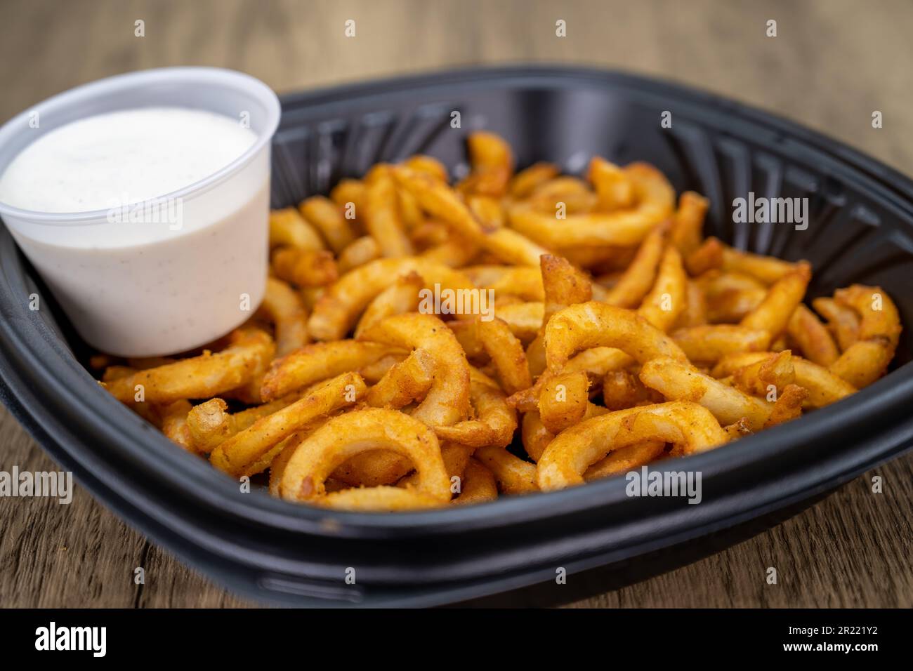 To go order of crispy curly fries packed in plastic container with ...