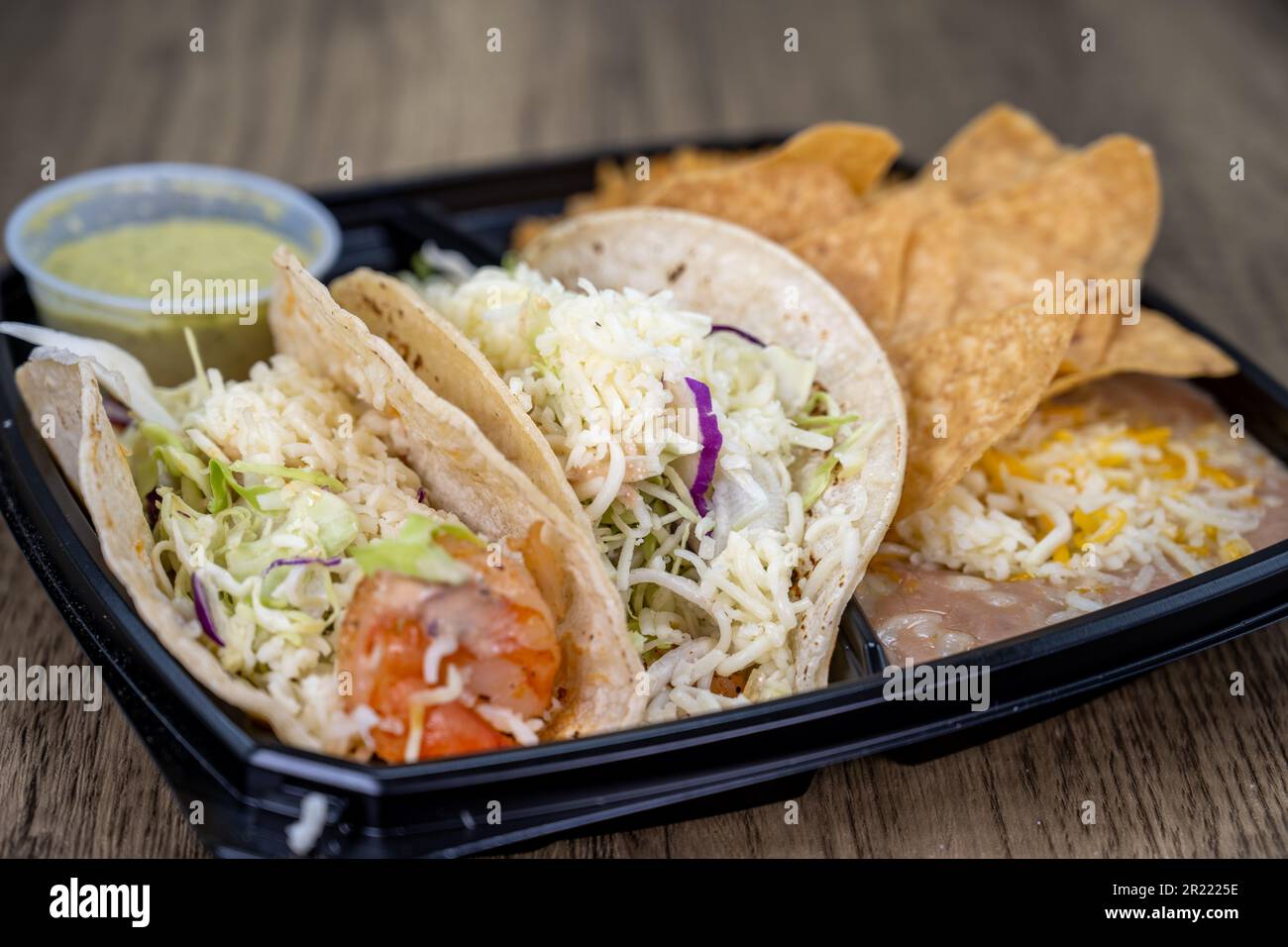 To go order of halibut fish tacos served with rice, beans, and chips in ...
