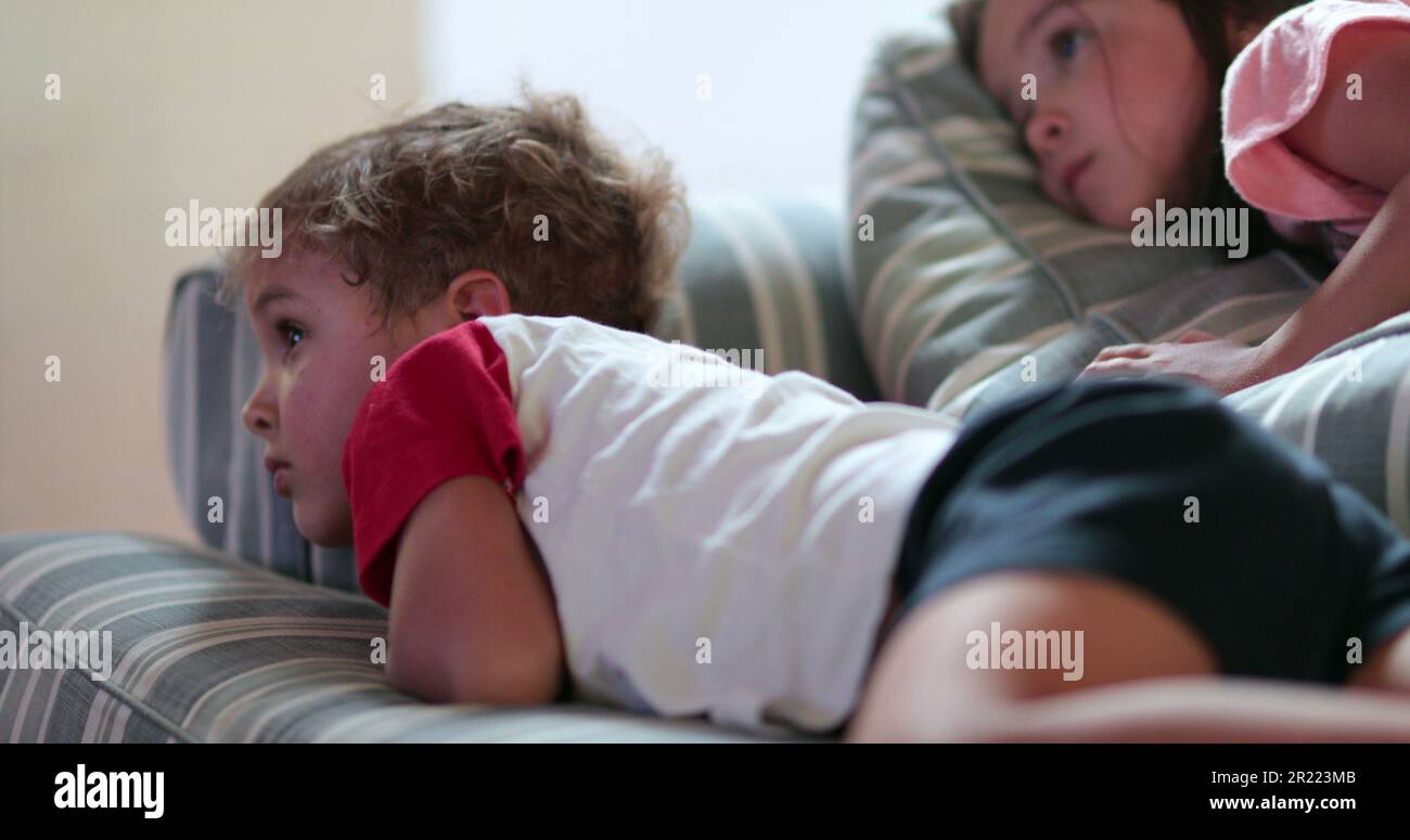 Kids laid on sofa watching movie at night. Children lying on couch ...
