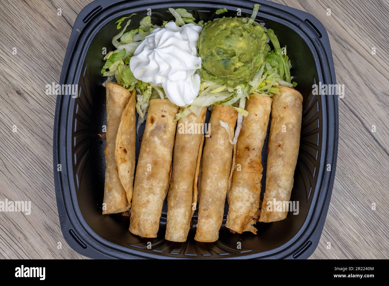 Overhead view of side order of deep fried, crispy taquitos packed in a ...