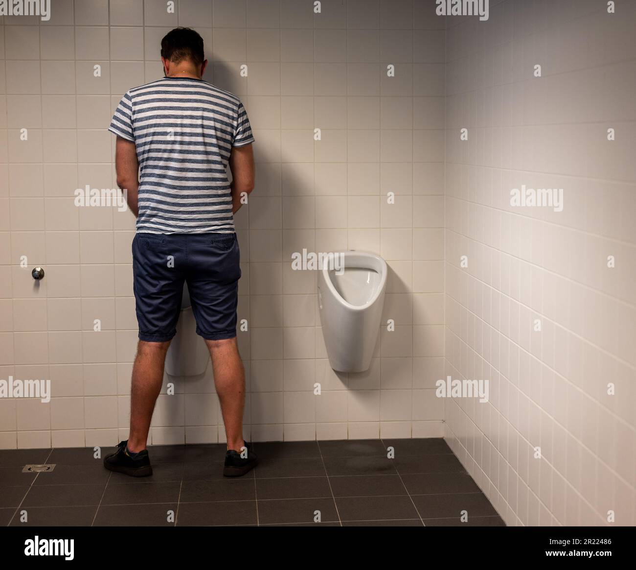 young man urinating in a public toilet, taken from behind Stock Photo ...