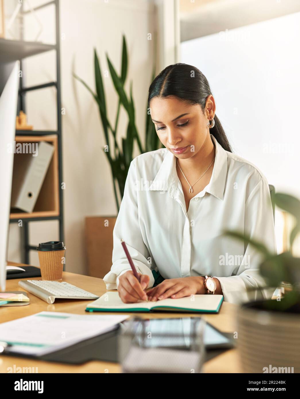 The words of a genius. a young businesswoman compiling notes at work ...