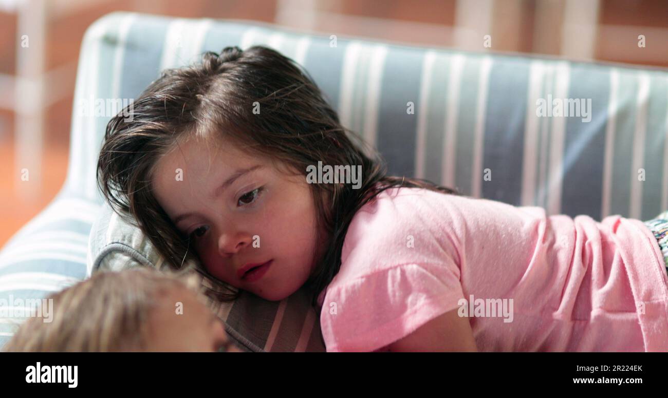 Sleepy little girl child laid on sofa yawning at night watching ...