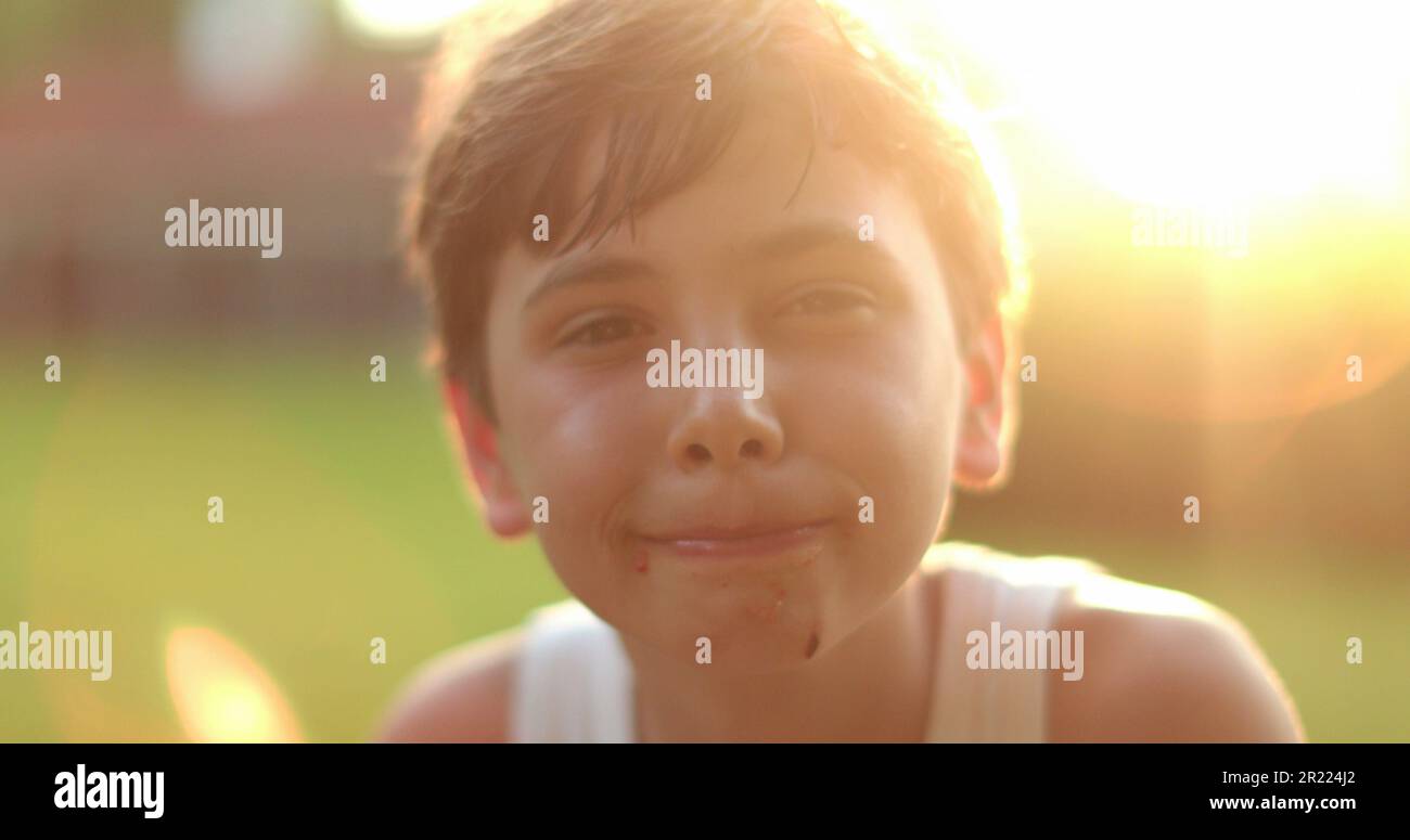 Handsome young boy child smiling to camera outside during sunset golden ...