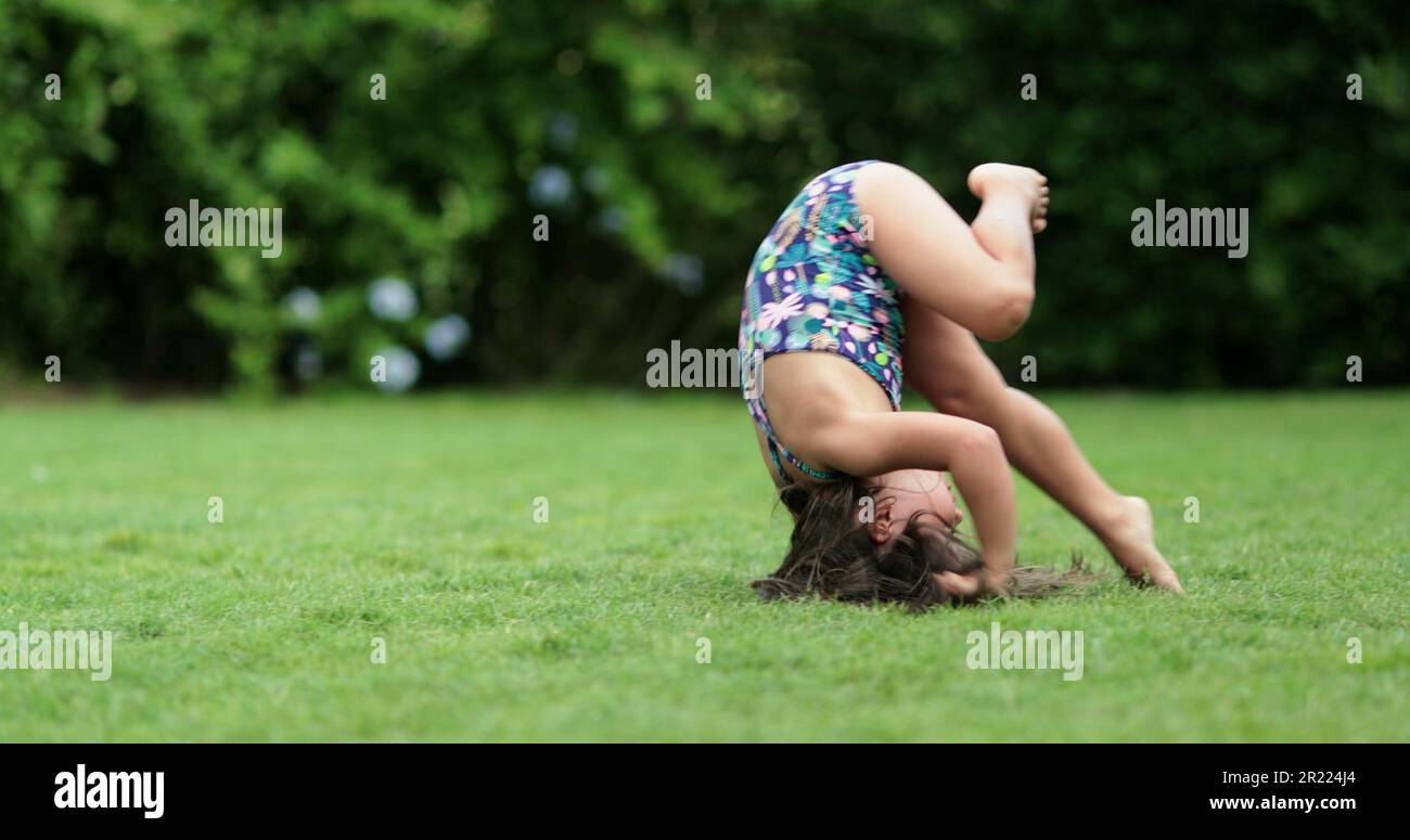 Happy child girl rolling on lawn outdoors, tumbling down, kid doing ...