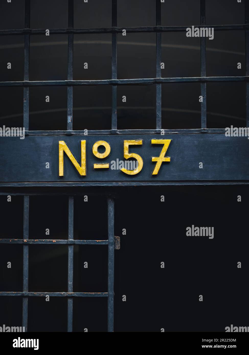 Yellow No. 57 number on a black forged iron gate dark moody art nouveau ...