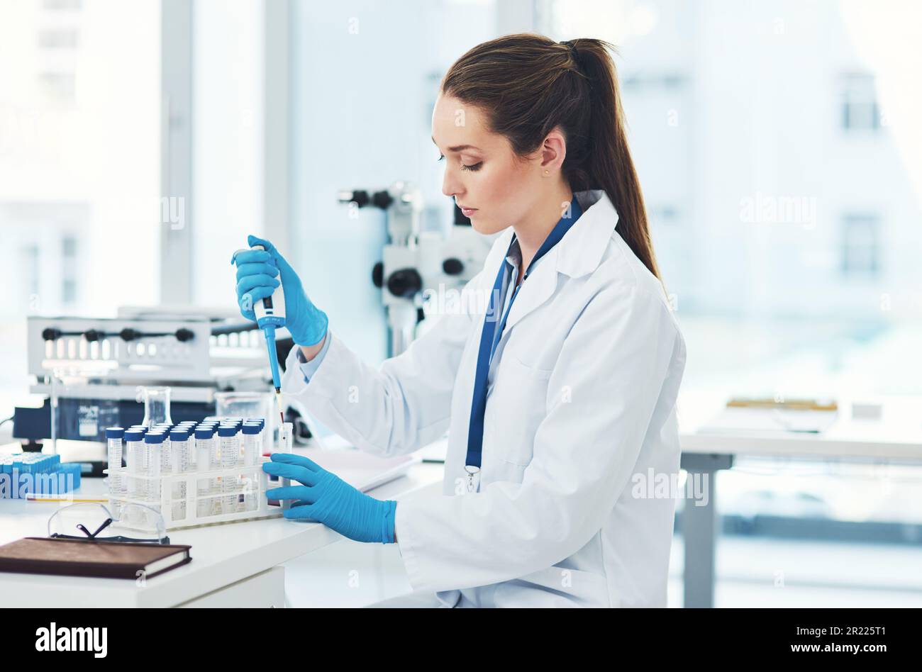 Thats one done. a focused young female scientist pouring a test sample ...