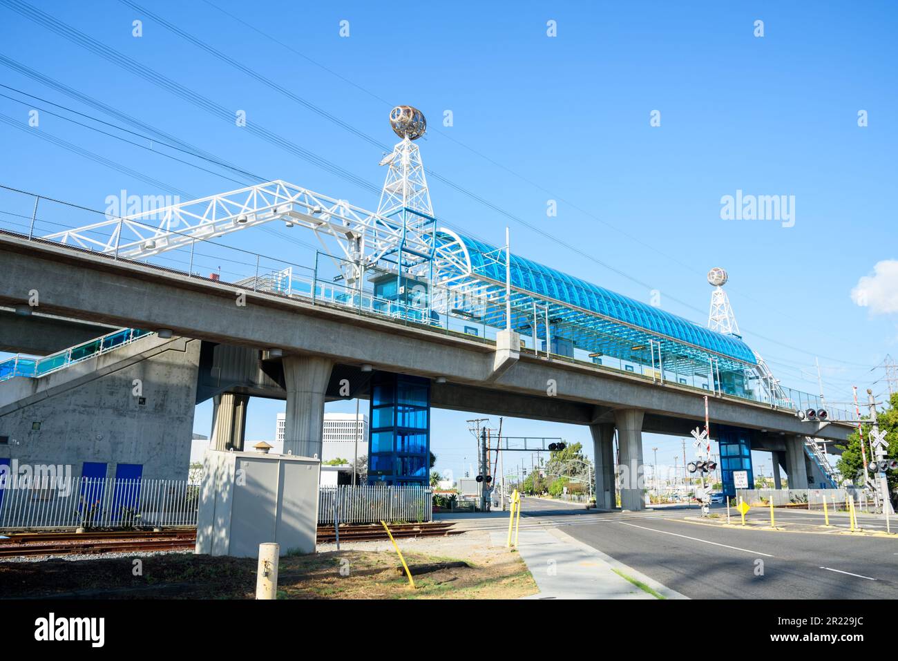 Modern elevated light rail station spanning a suburban road on a clear ...