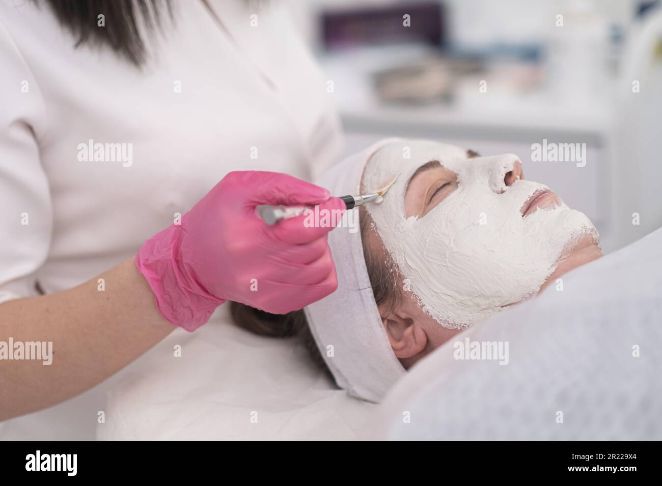 skincare expert applying a nourishing face mask to her client with ...