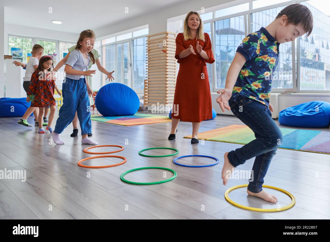 Small nursery school children with female teacher on floor indoors in ...