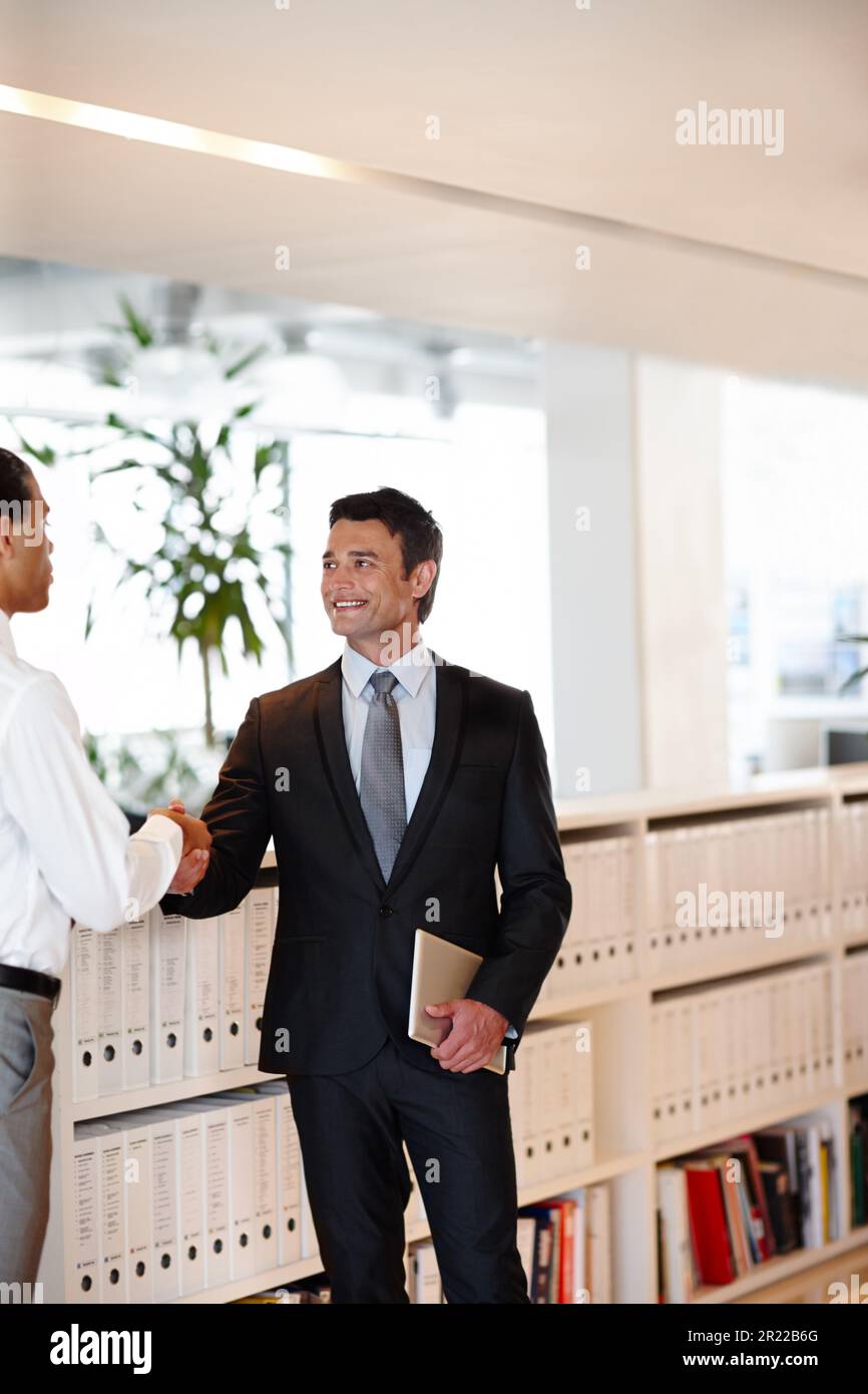 Its great to meet you. Two suit-clad businessmen shaking hands while in ...