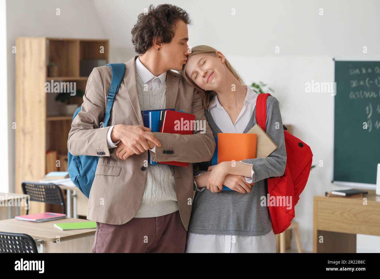 Cute teenage couple with books in classroom Stock Photo - Alamy