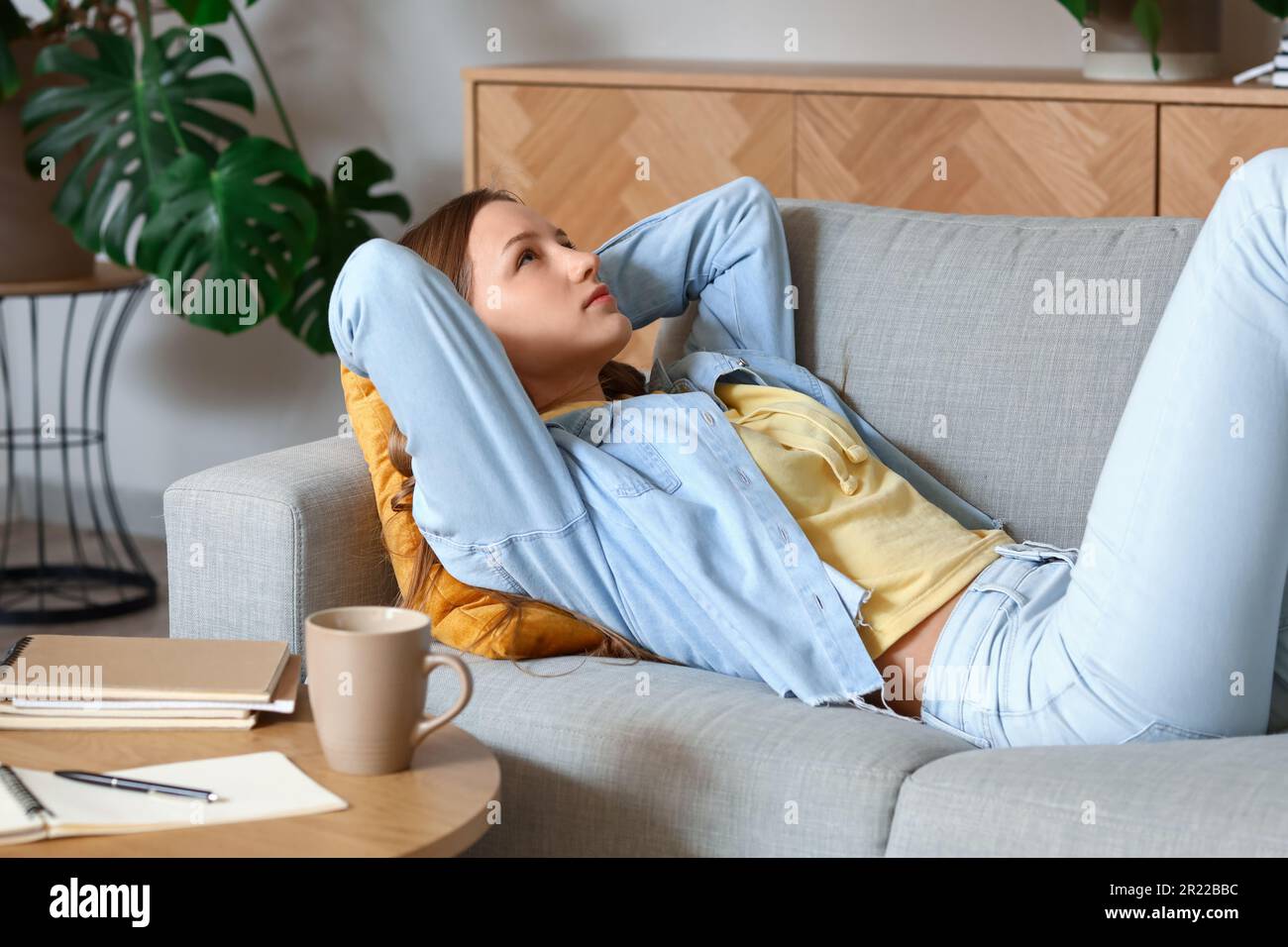 Thoughtful teenage girl lying on sofa at home Stock Photo - Alamy