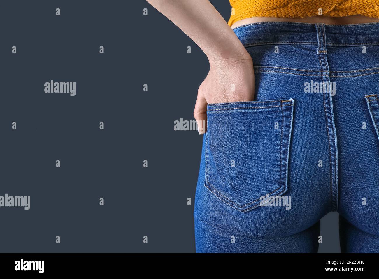 Young woman in skinny jeans on dark background, back view Stock Photo ...