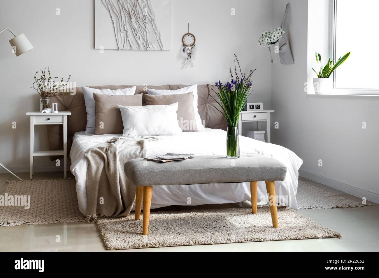 Interior of bright bedroom with beautiful iris flowers on bedside bench Stock Photo - Alamy