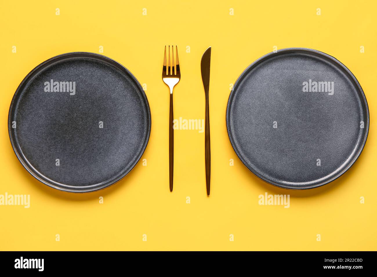 Table setting with clean plates and cutlery on yellow background Stock ...