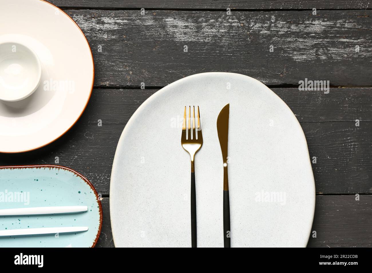 Table setting with clean plates and cutlery on black wooden table Stock ...