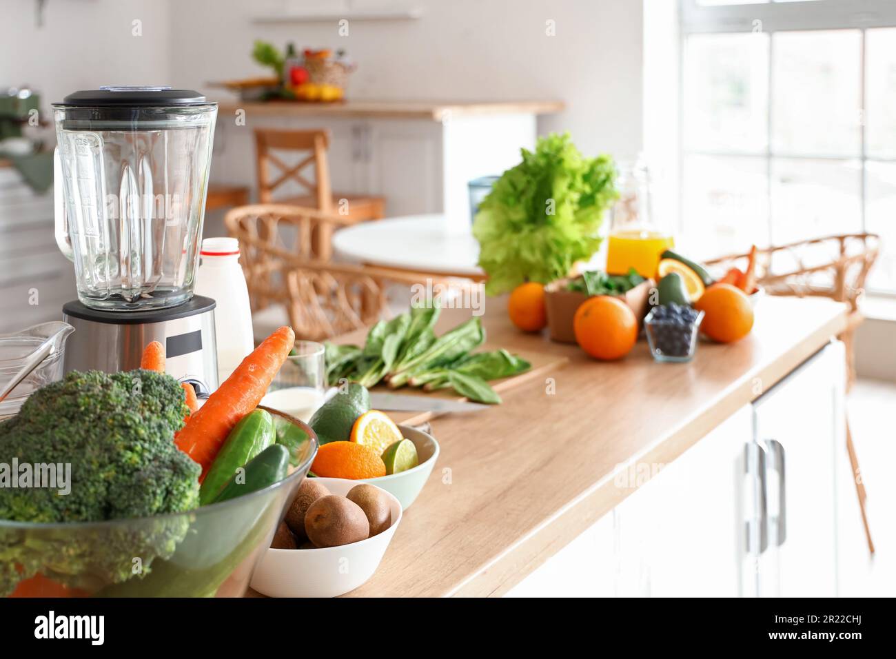 Blender with fresh vegetables and fruits on counter in kitchen, closeup ...