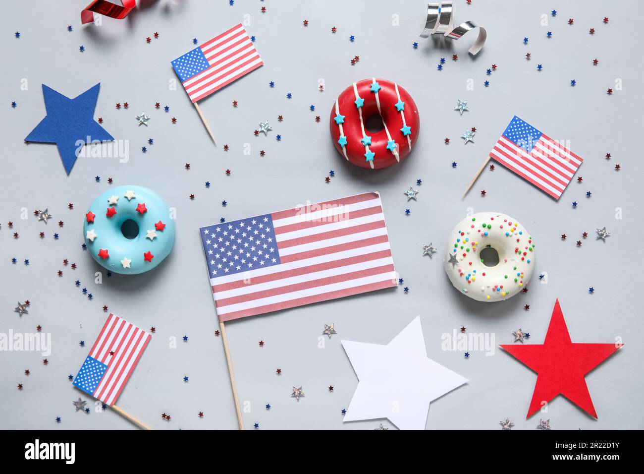 Composition with donuts, USA flags and confetti on grey background ...
