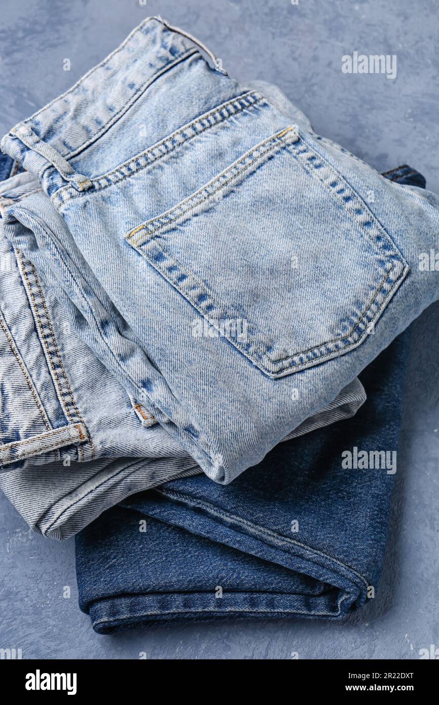 Different folded denim jeans on grunge blue background Stock Photo - Alamy