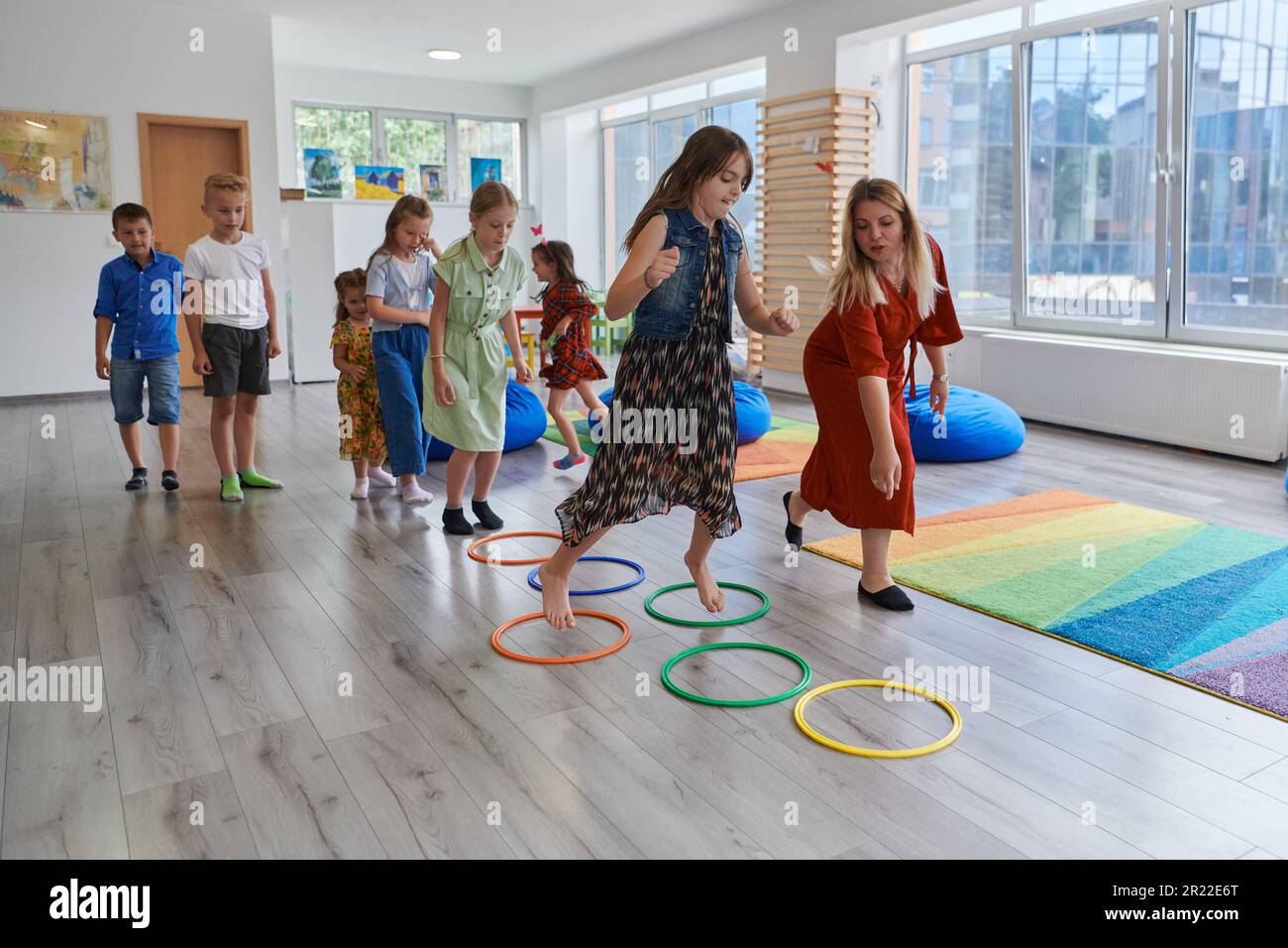 Small nursery school children with female teacher on floor indoors in ...