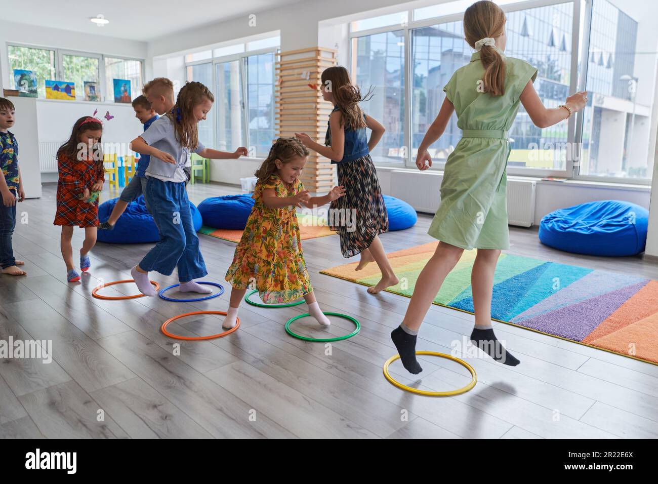Small nursery school children with female teacher on floor indoors in ...