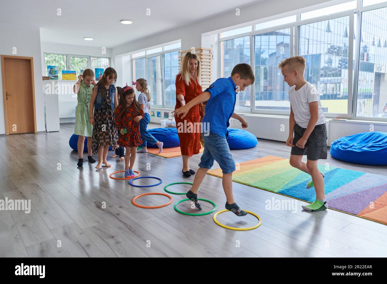Small nursery school children with female teacher on floor indoors in ...