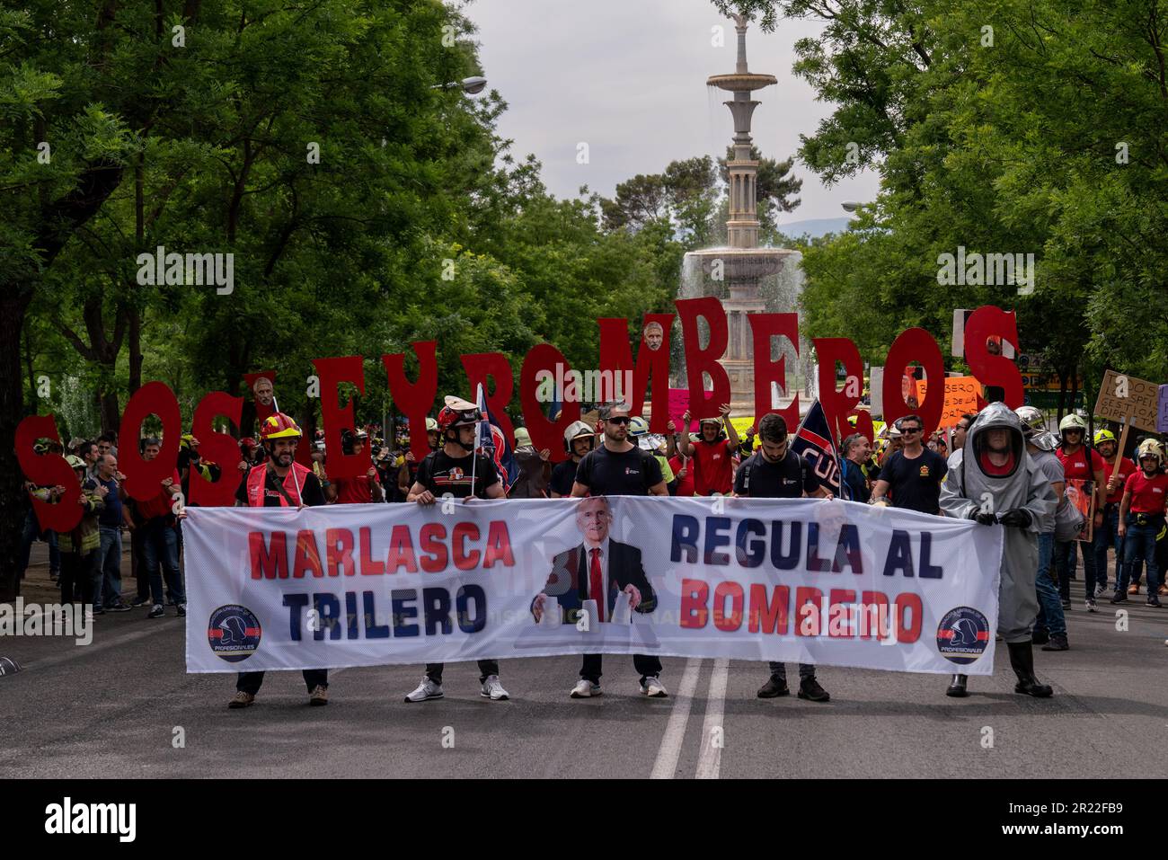 Firefighters hold a big banner as other protesters hold letter placards ...