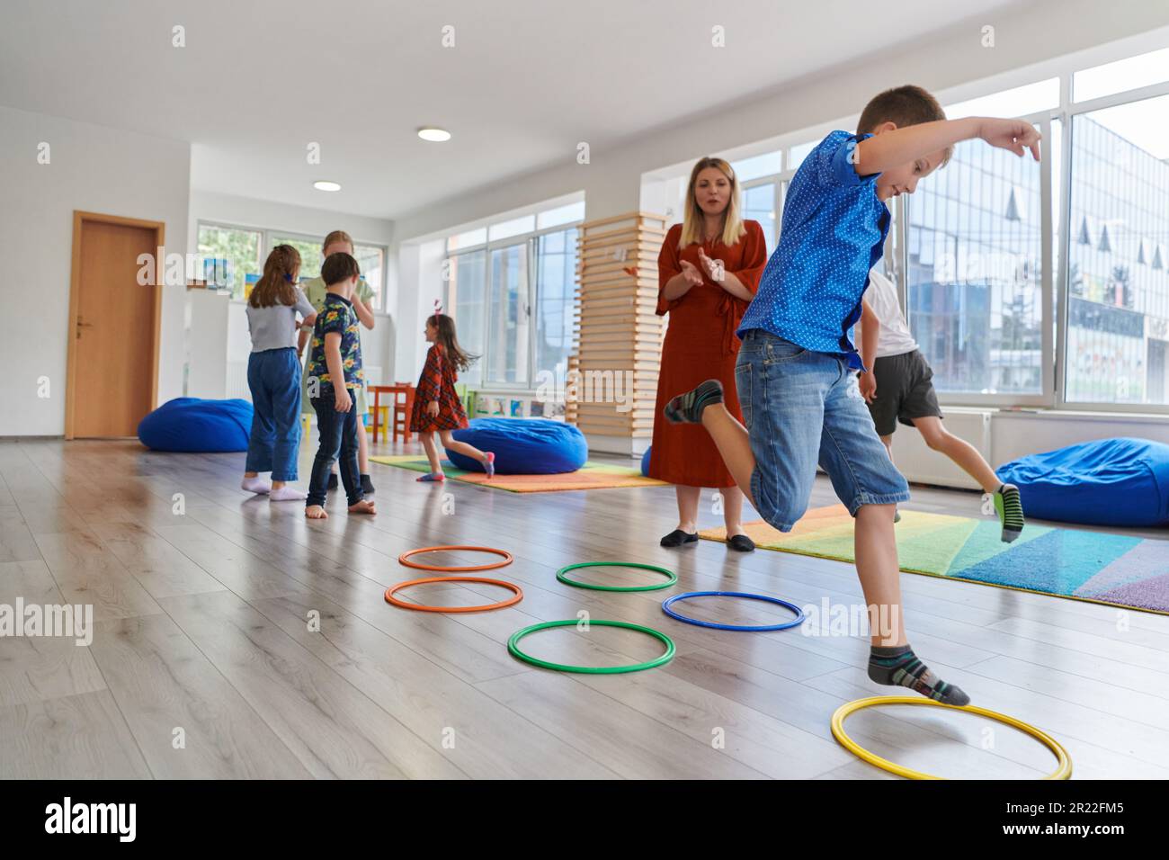 Small nursery school children with female teacher on floor indoors in ...