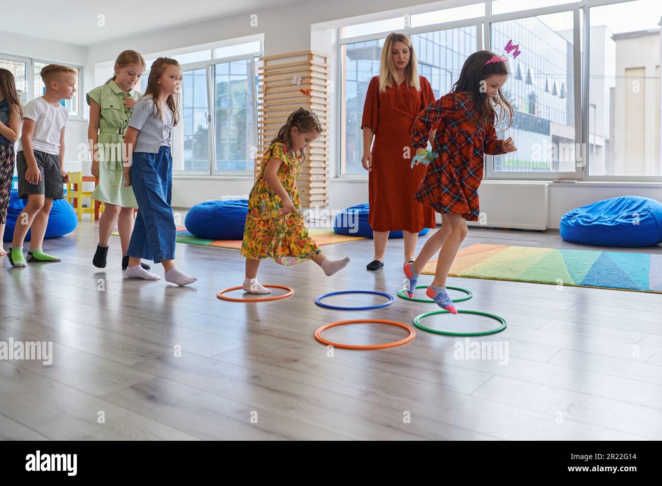 Small nursery school children with female teacher on floor indoors in ...