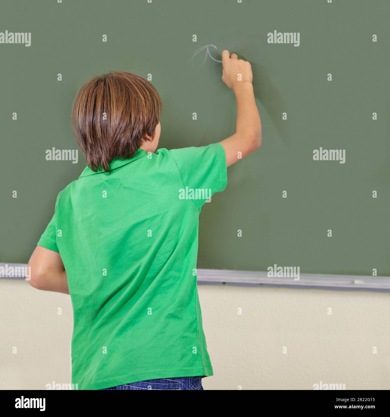 The best way to learn. A young boy writing on the blackboard at school ...