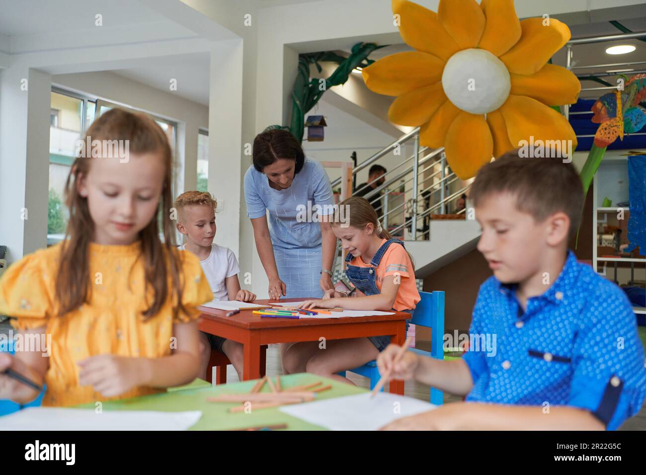 Creative kids during an art class in a daycare center or elementary school classroom drawing ...