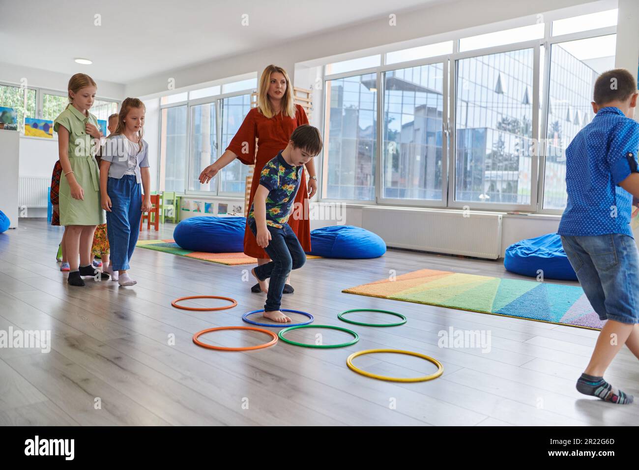 Small nursery school children with female teacher on floor indoors in ...