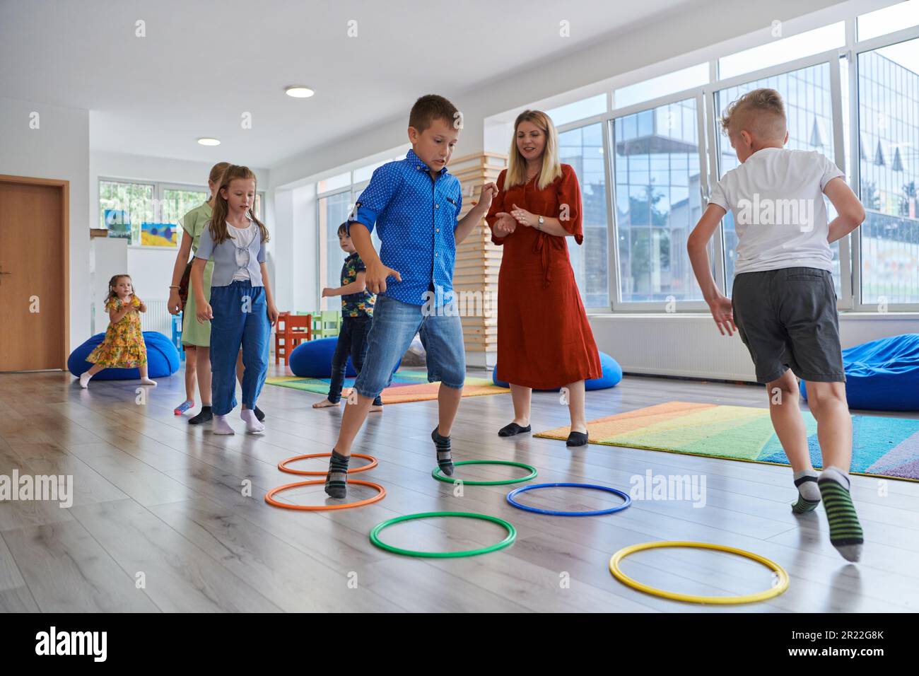 Small nursery school children with female teacher on floor indoors in ...