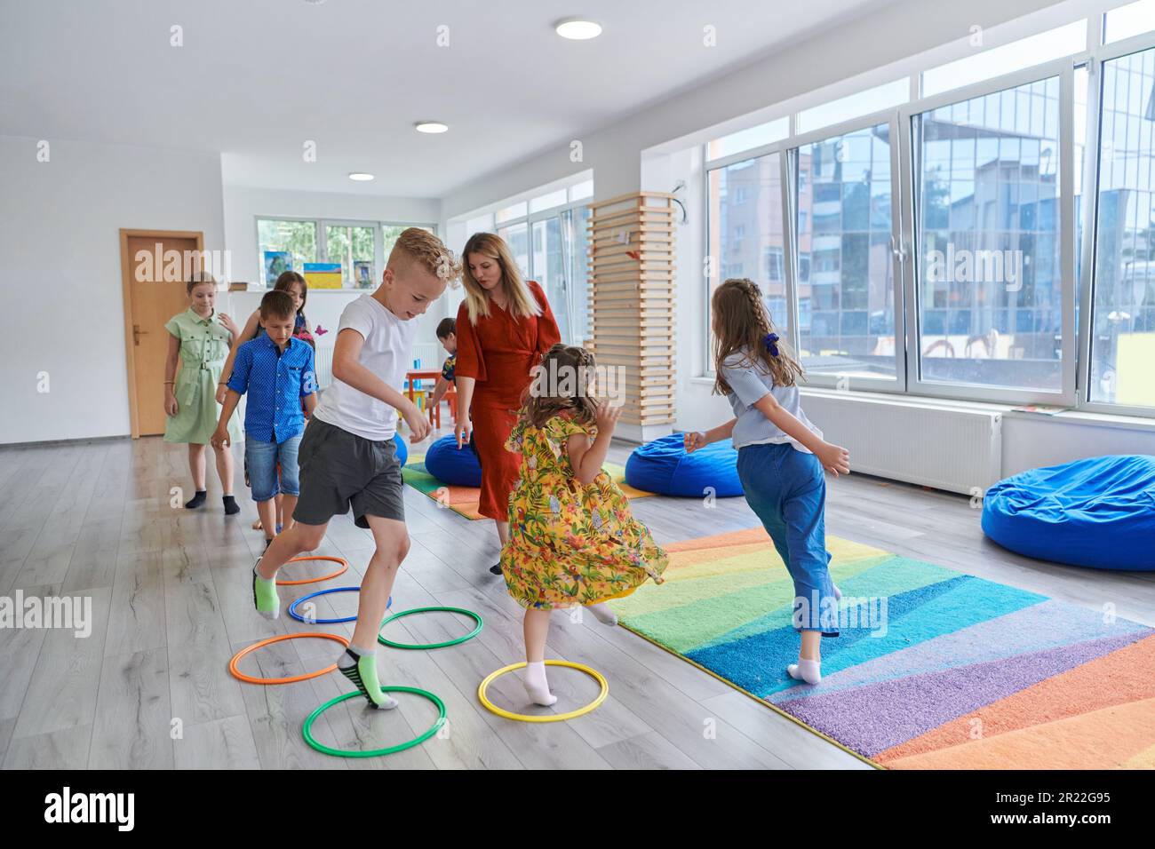 Small nursery school children with female teacher on floor indoors in ...