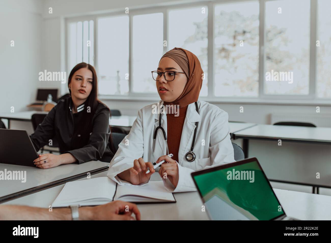 In a modern meeting room, a Muslim female doctor wearing a hijab ...
