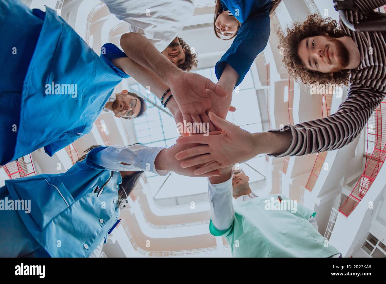 A group of doctors and a medical nurse join their hands together ...