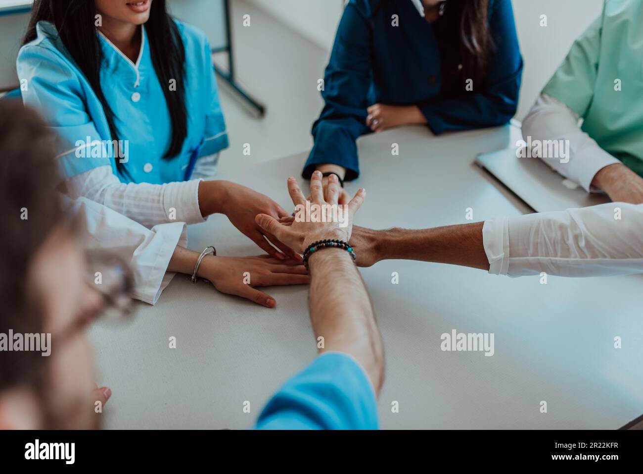 A group of doctors and a medical nurse join their hands together on a ...