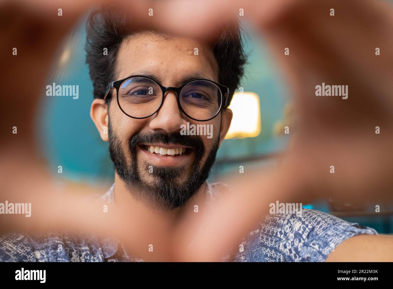 I love you. Happy indian man at home living room couch makes symbol of ...