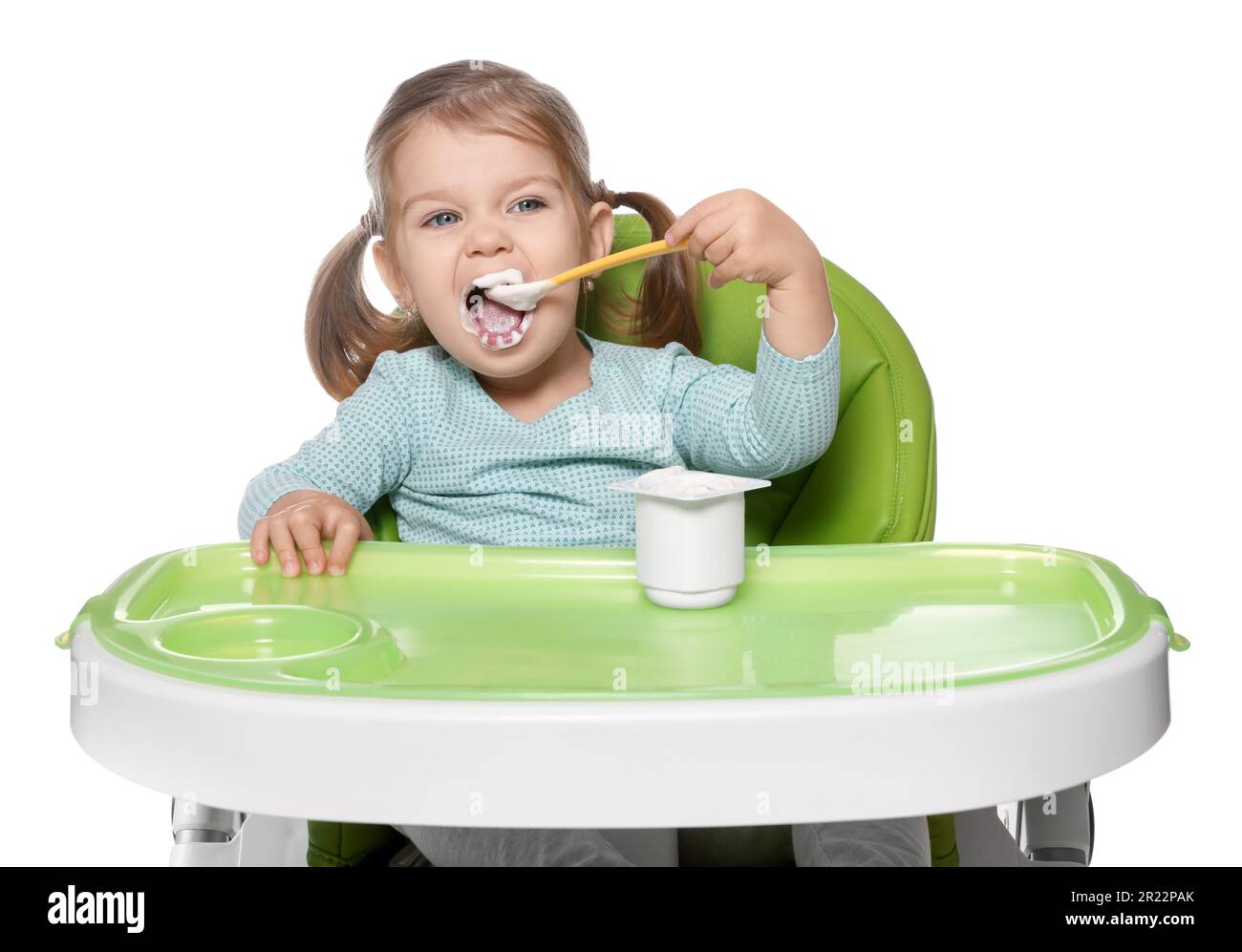 Cute little child eating tasty yogurt from plastic cup with spoon in ...