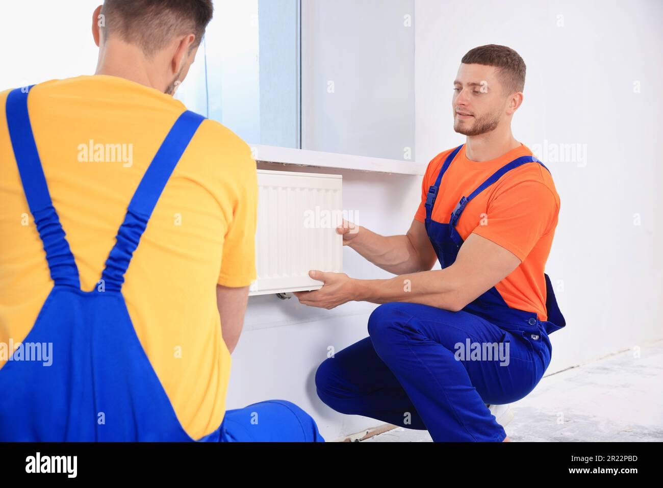 Professional plumbers installing new heating radiator in room Stock ...