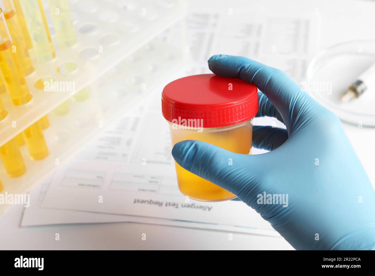 Nurse holding container with urine sample at table, closeup and space ...
