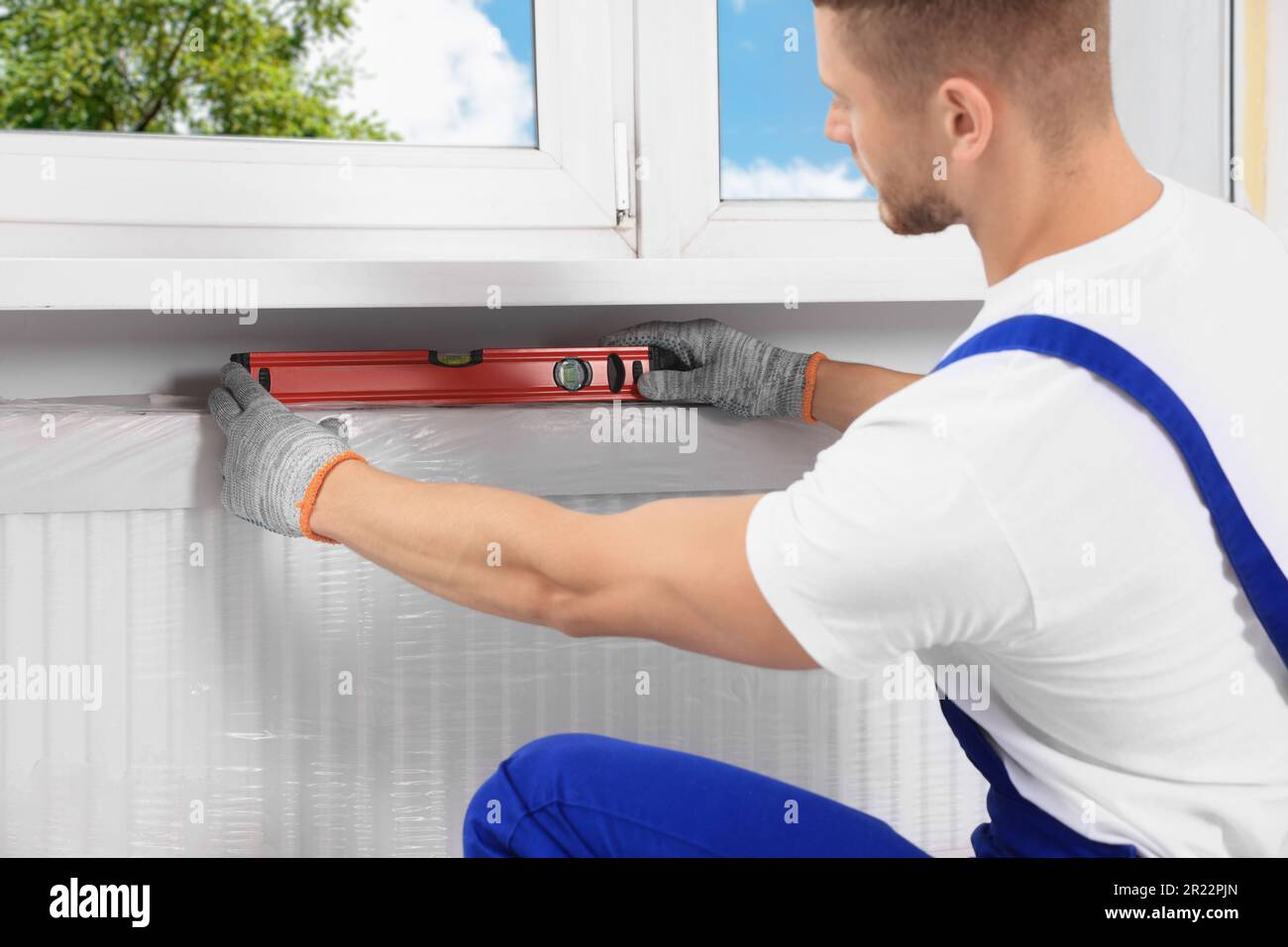 Professional plumber using bubble level for installing new heating ...