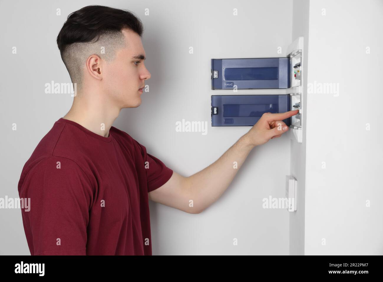 Young handyman pressing switch on electrical panel board indoors Stock ...