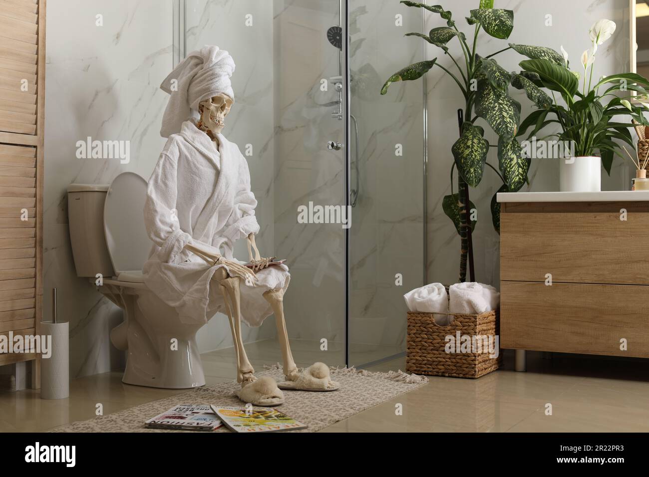 Skeleton in bathrobe with mobile phone sitting on toilet bowl Stock ...