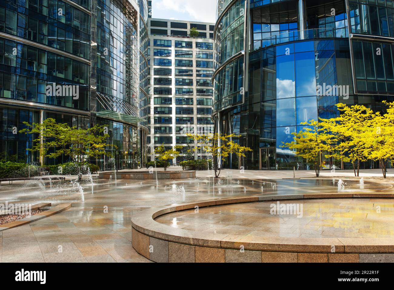 Beautiful fountain and trees near buildings in city Stock Photo - Alamy