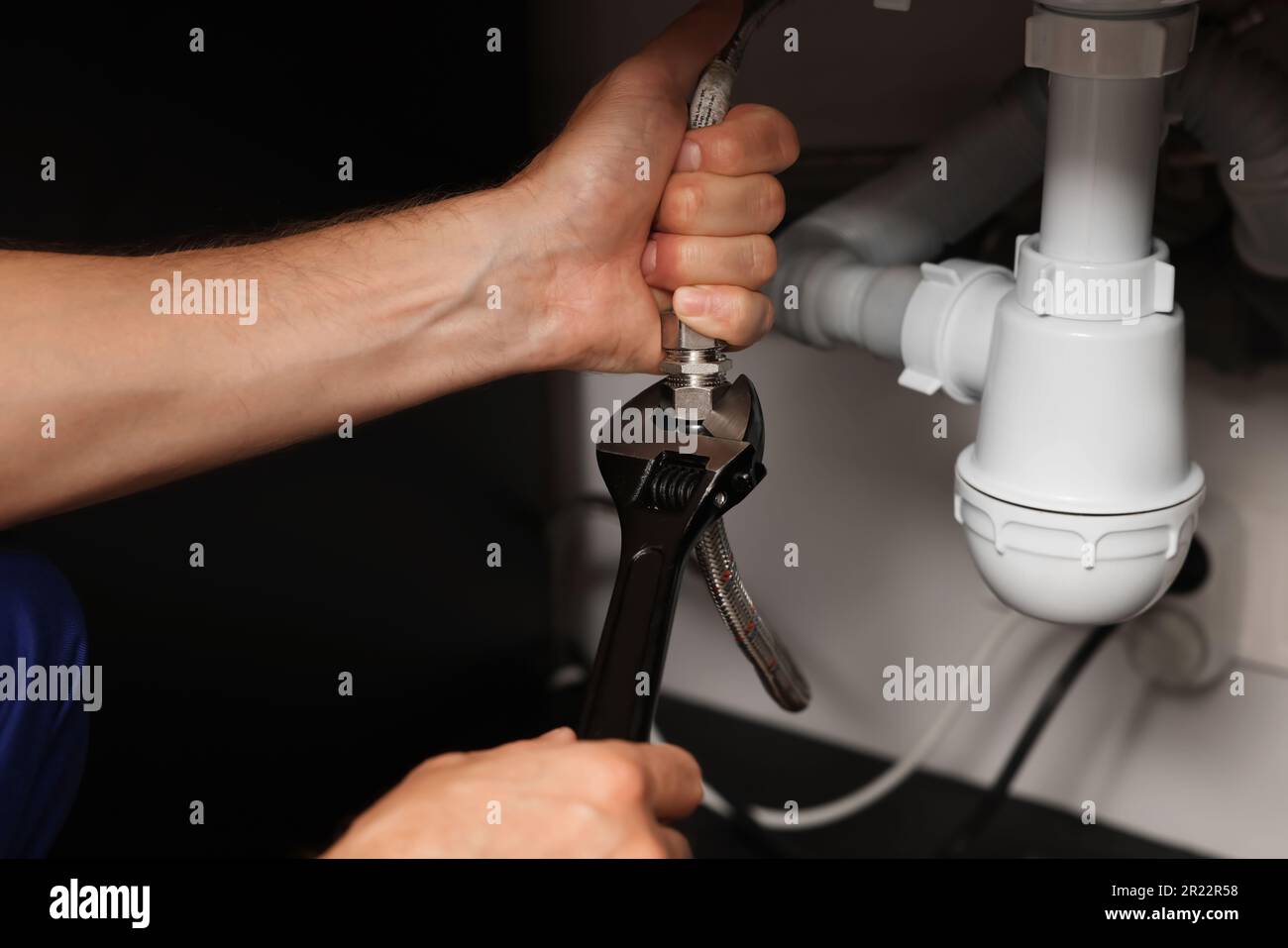Professional plumber with adjustable wrench fixing sink, closeup Stock ...